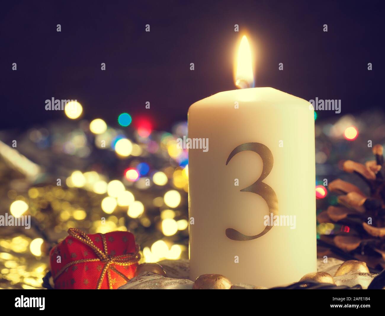 Third Advent candle, burning candle with number three and blurred ...