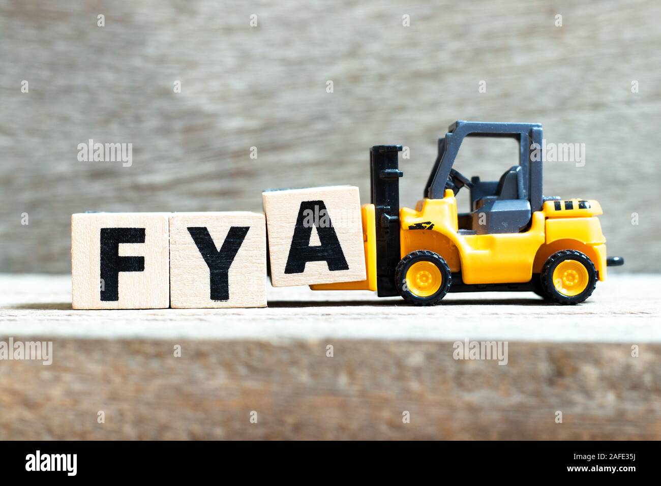 Toy forklift hold letter block A to complete word FYA (Abbreviation of ...
