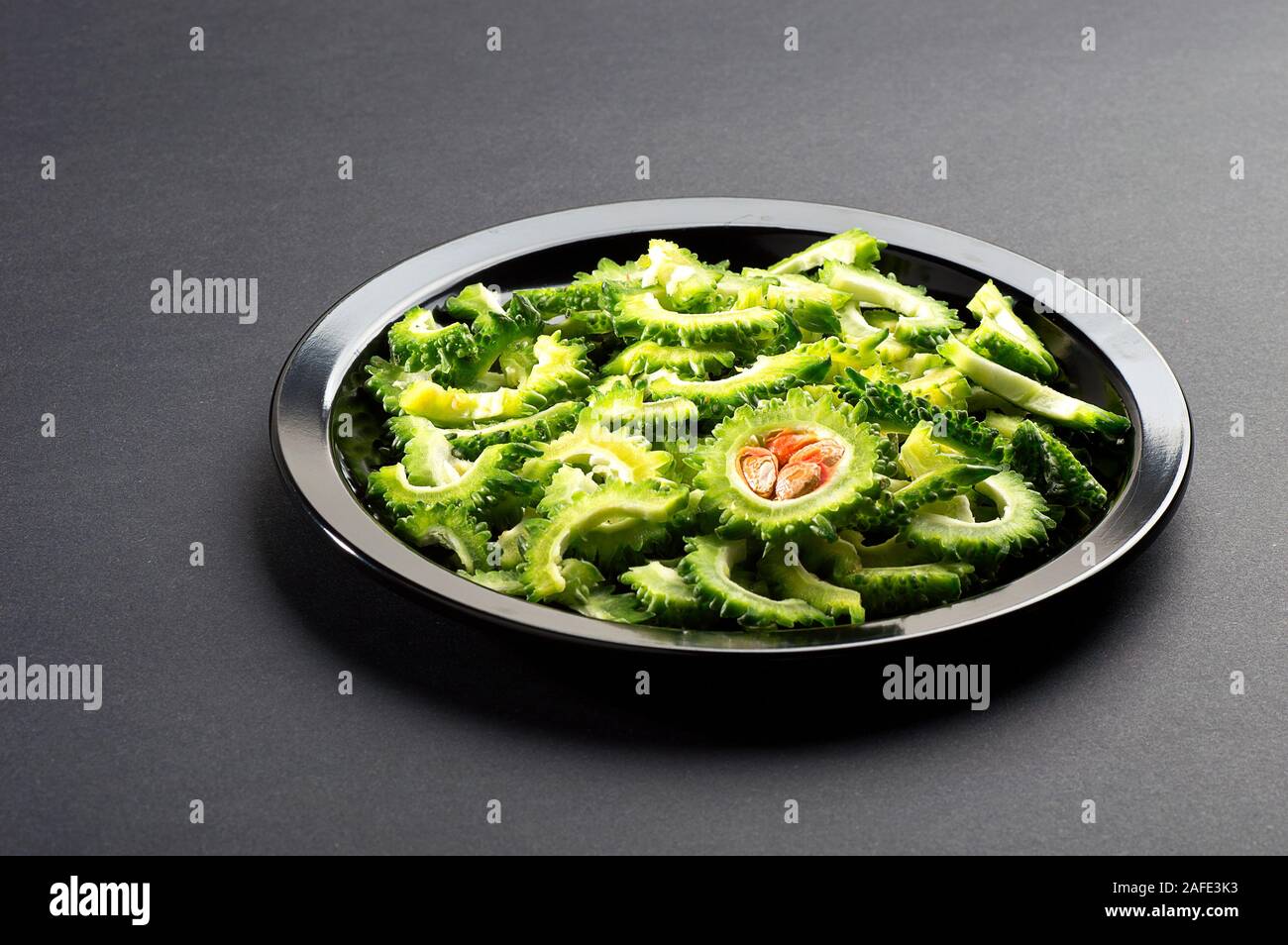 Bitter melon or bitter gourd in black plate on black background Stock ...