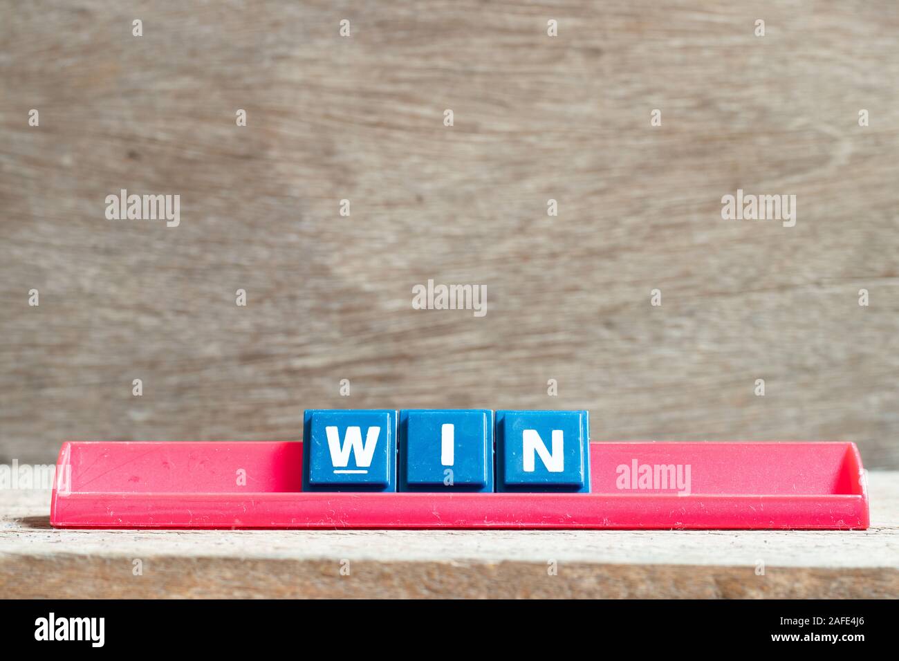 Tile letter on red rack in word win on wood background Stock Photo - Alamy