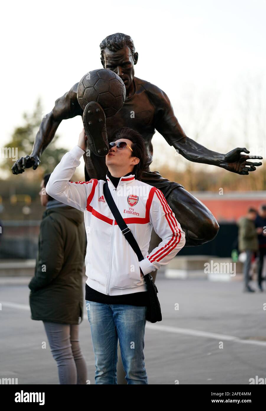 An Arsenal fan poses with the statue of former Arsenal player Dennis ...