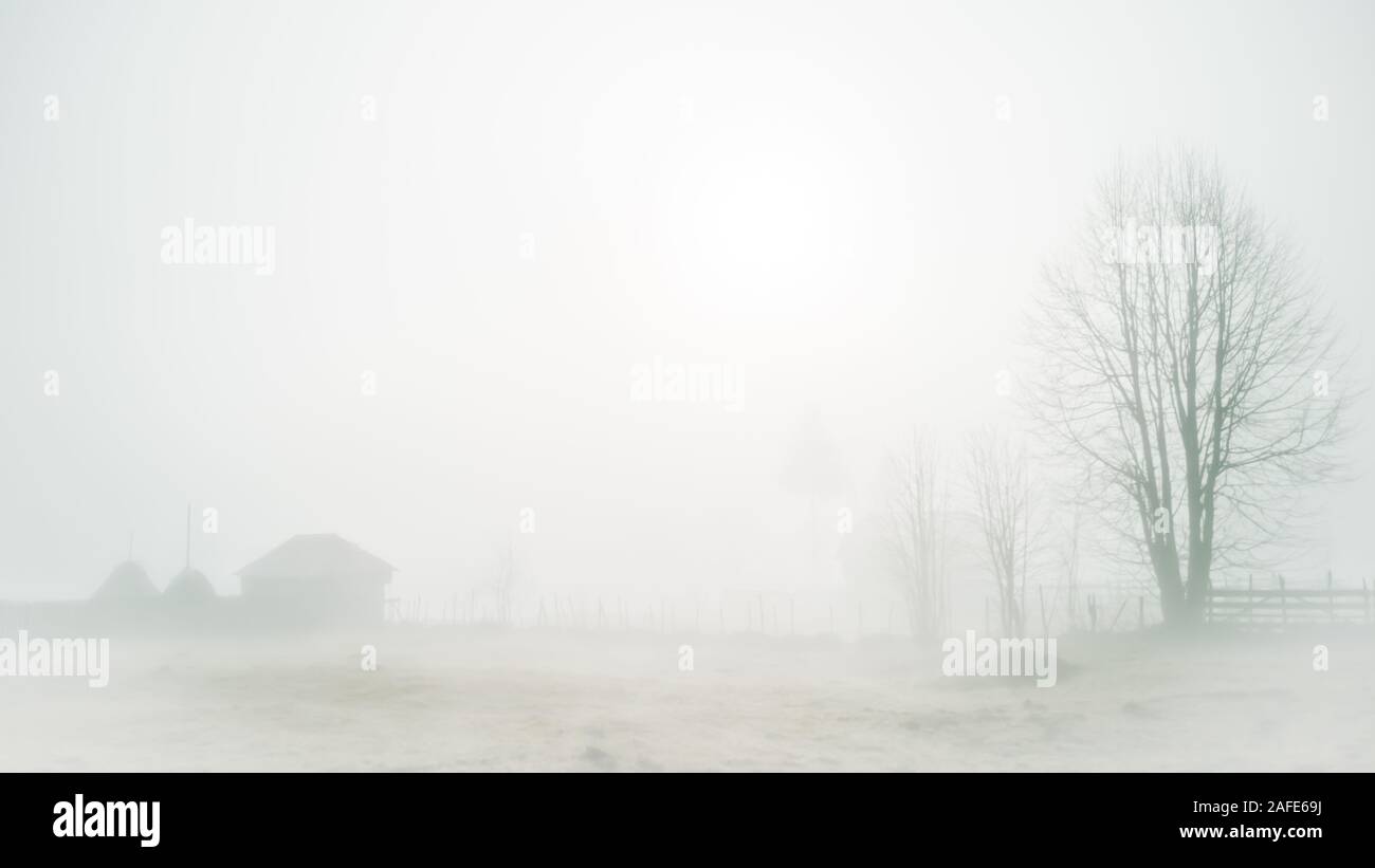 Misty countryside landscape in a mountain village. A foggy morning with ...
