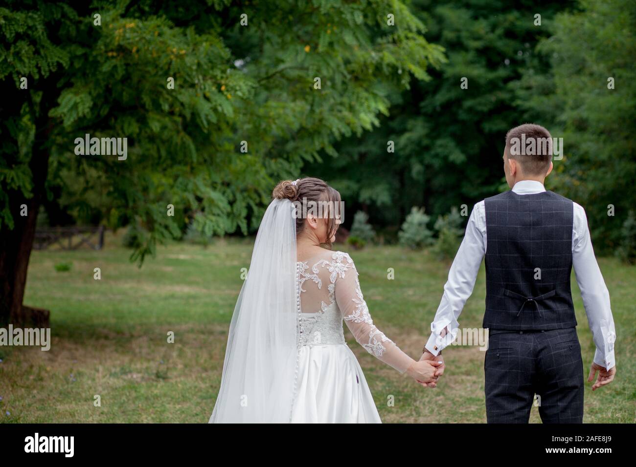 Happy bride and groom holding hands and walking in garden wedding day ...