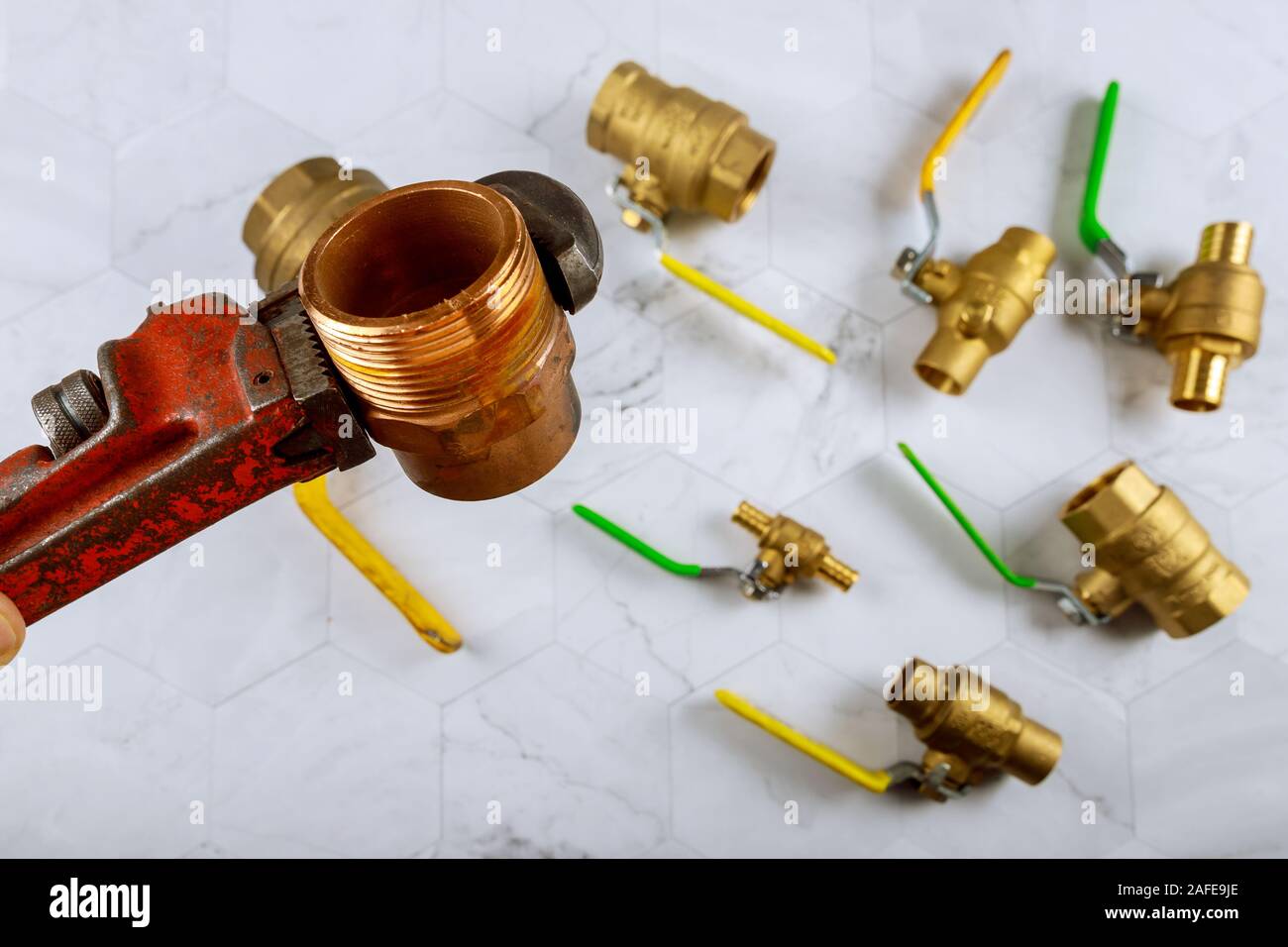 Adjustable monkey wrench and brass fittings on natural floor background ...
