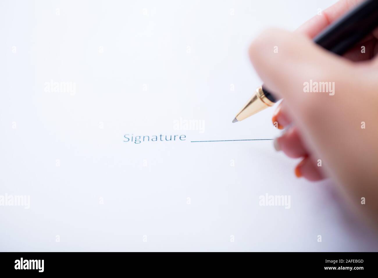 Close up girl hand putting signature on document. She situating at desk ...