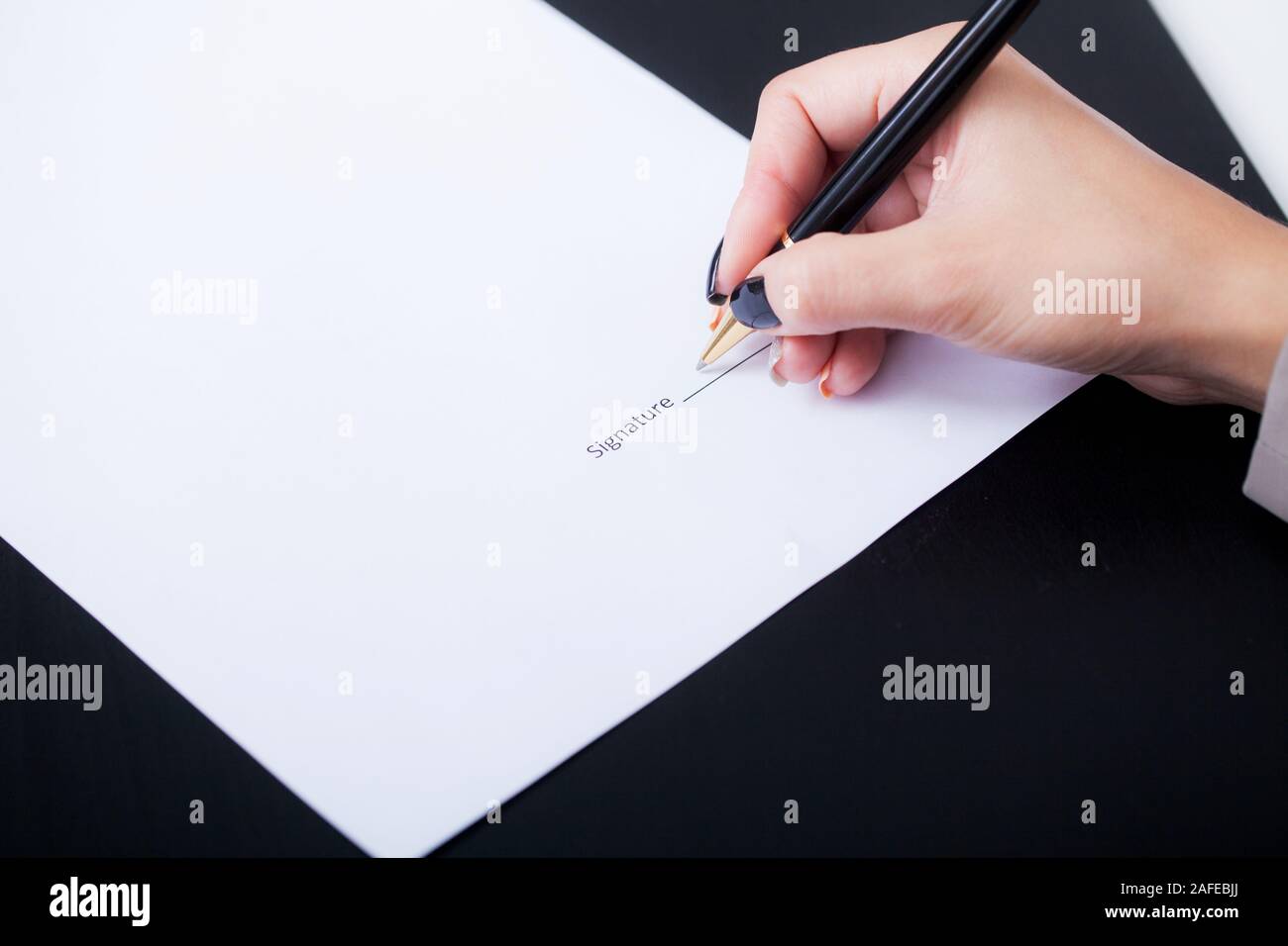 Close up girl hand putting signature on document. She situating at desk ...