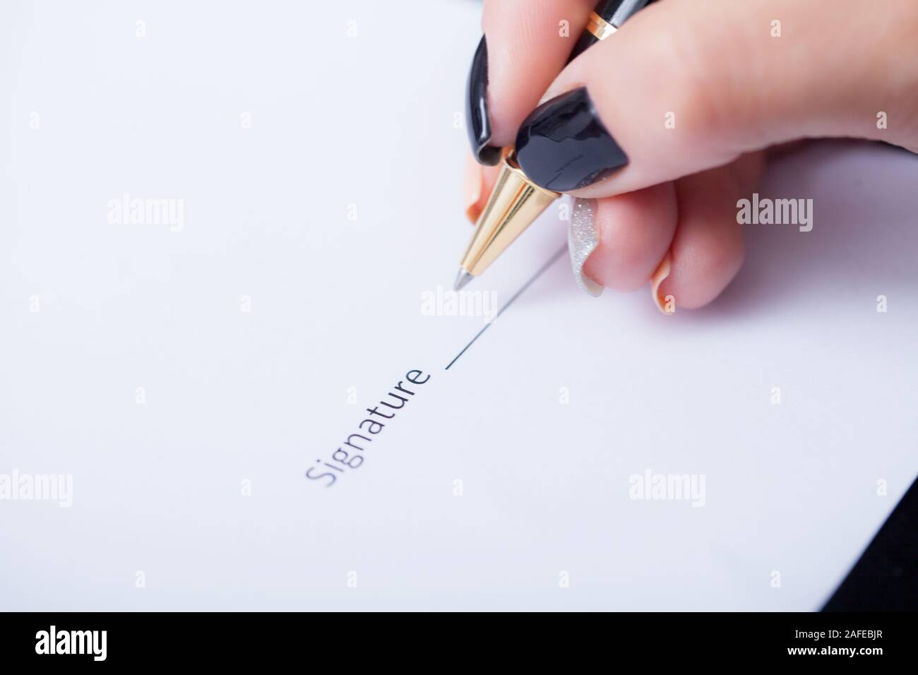 Close up girl hand putting signature on document. She situating at desk ...