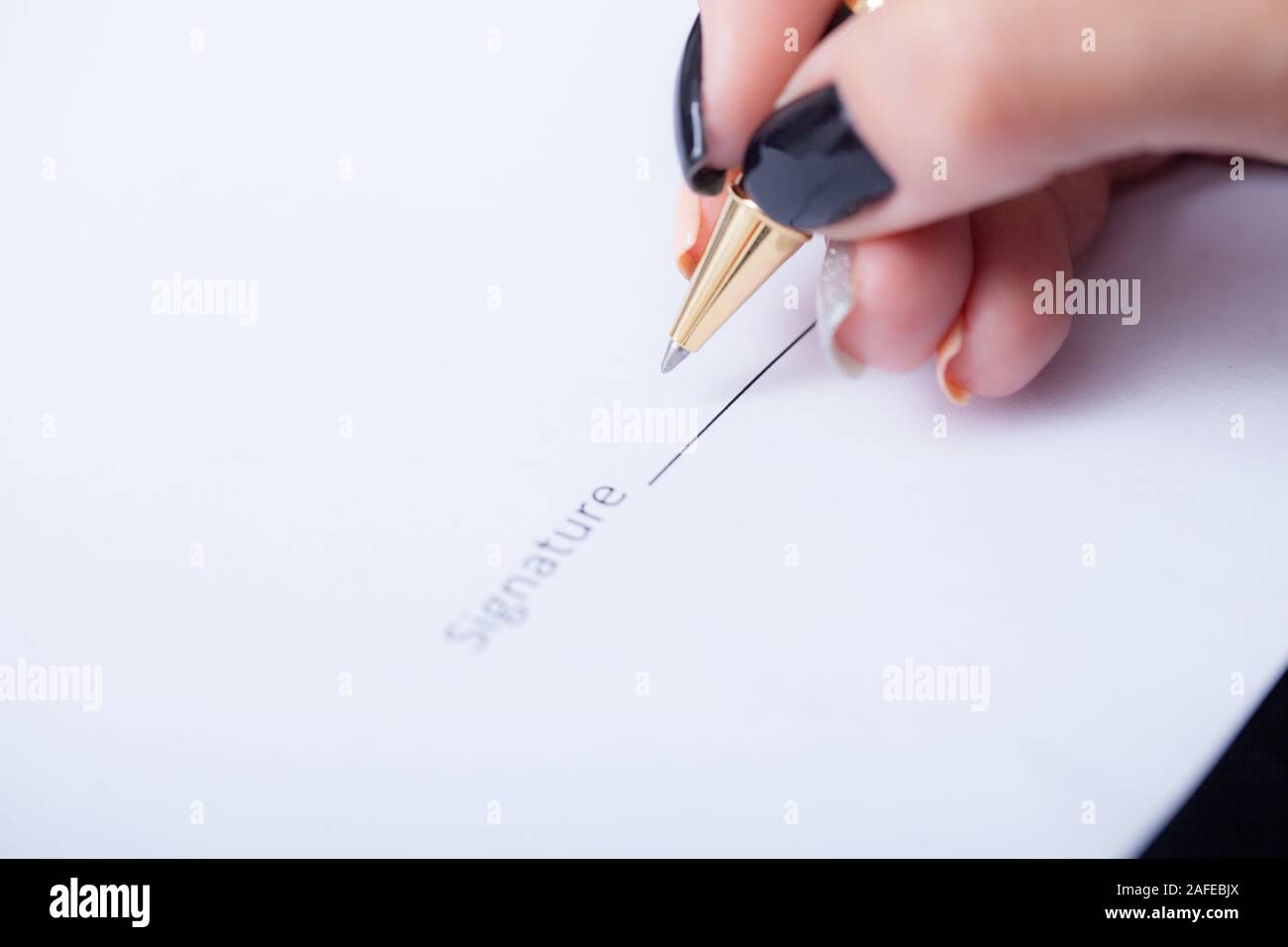 Close up girl hand putting signature on document. She situating at desk ...