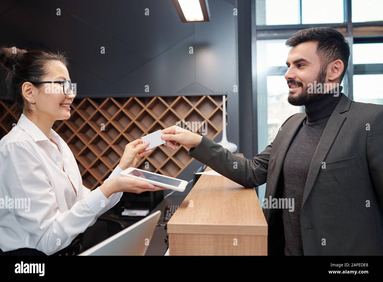 Young smiling business traveler taking card from hotel room by ...