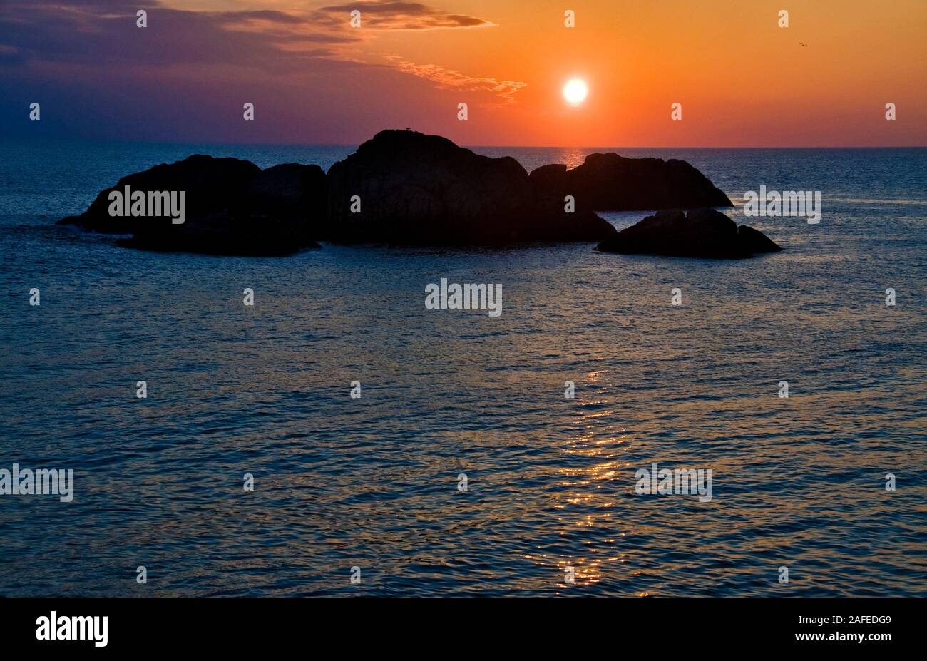 The blood-red April sun sets in the ocean west of Kirkehamn oin the ...