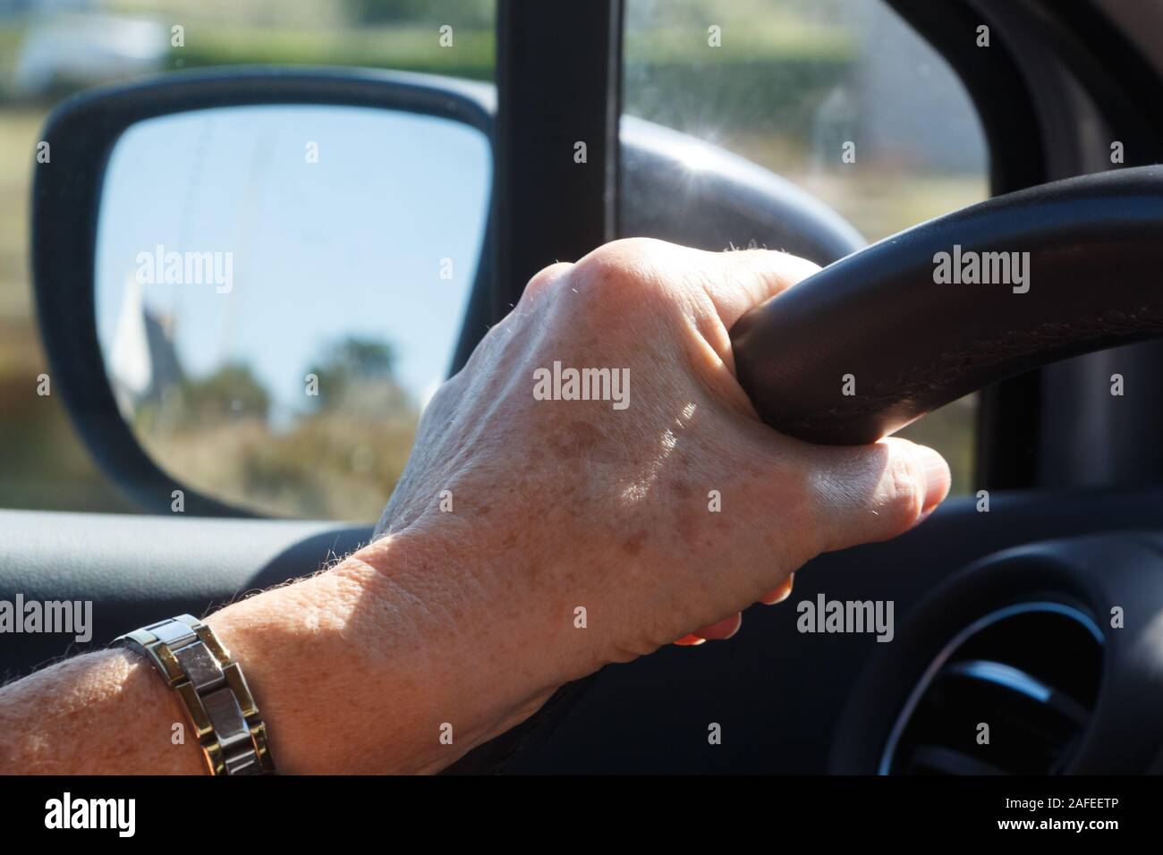 Hand on a steering wheel and rear-view mirror Stock Photo - Alamy