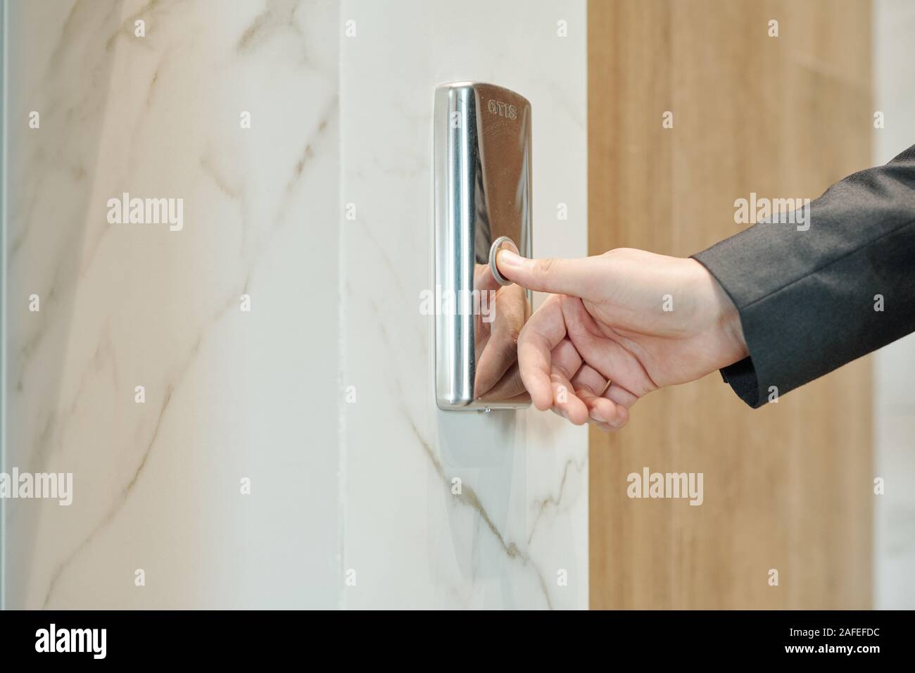 Hand of businessman pushing button on the wall while standing by ...