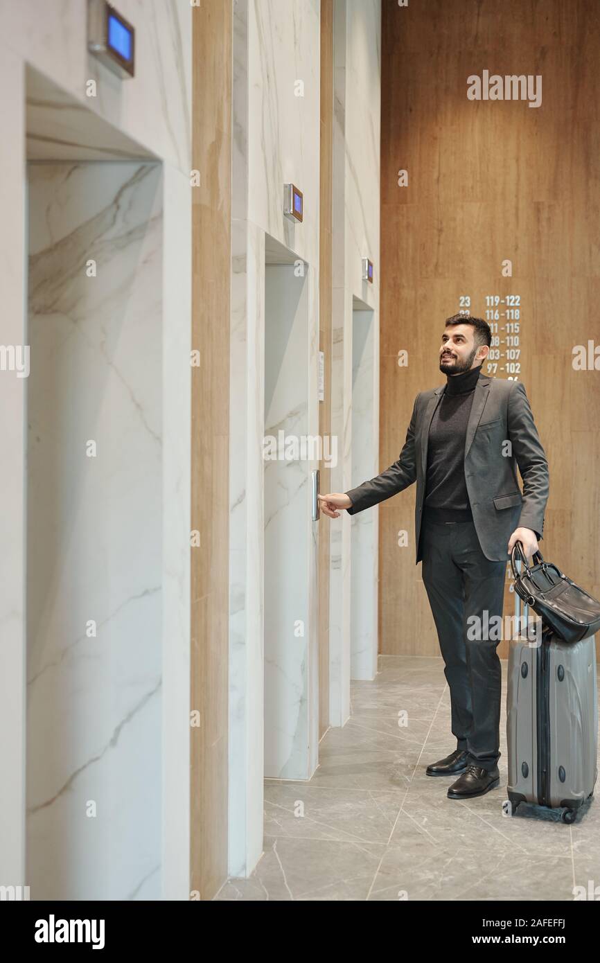 Businessman pushing button on the wall while standing by one of ...