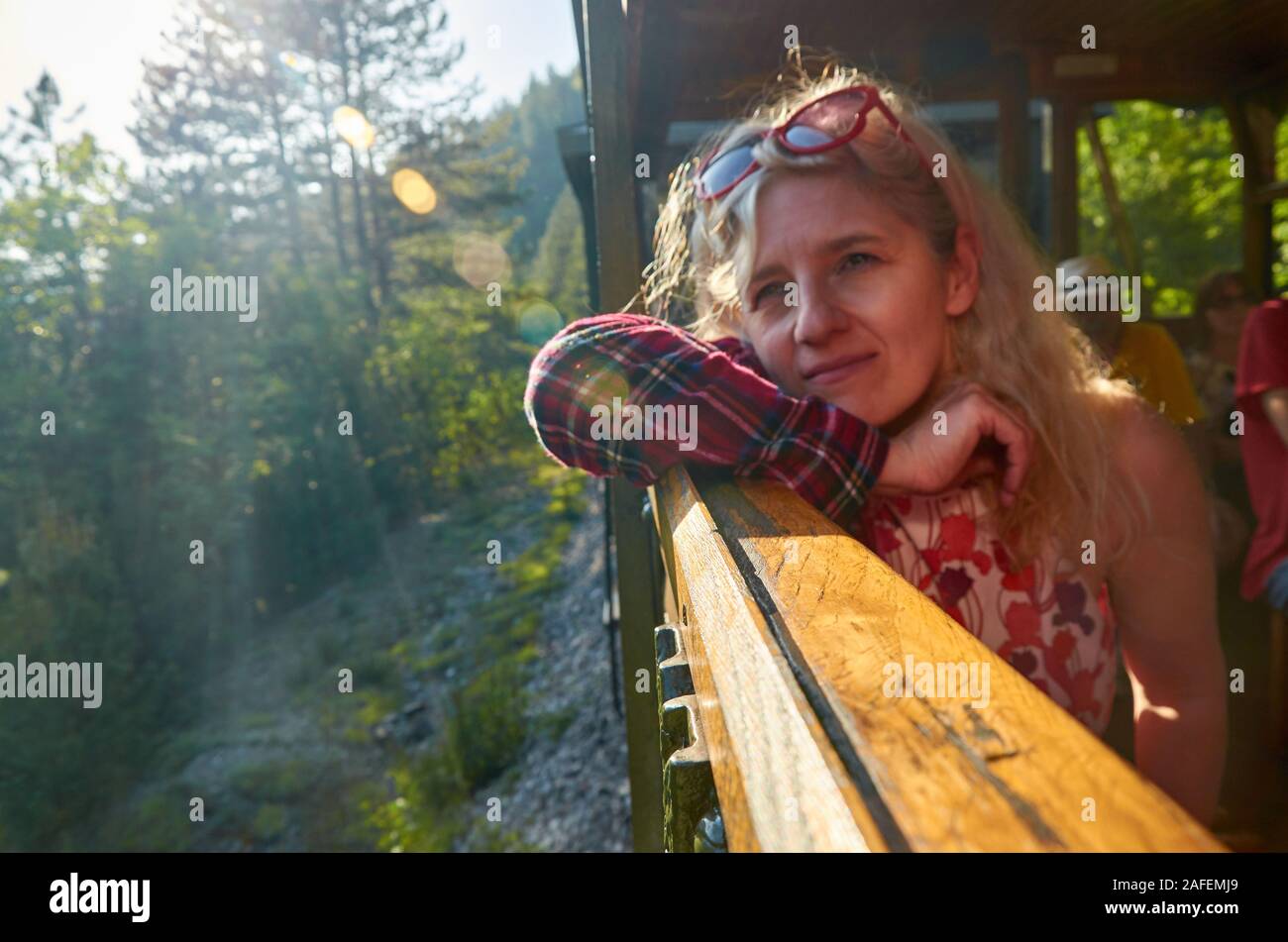 Woman leaned out off a train window and looking out while traveling ...