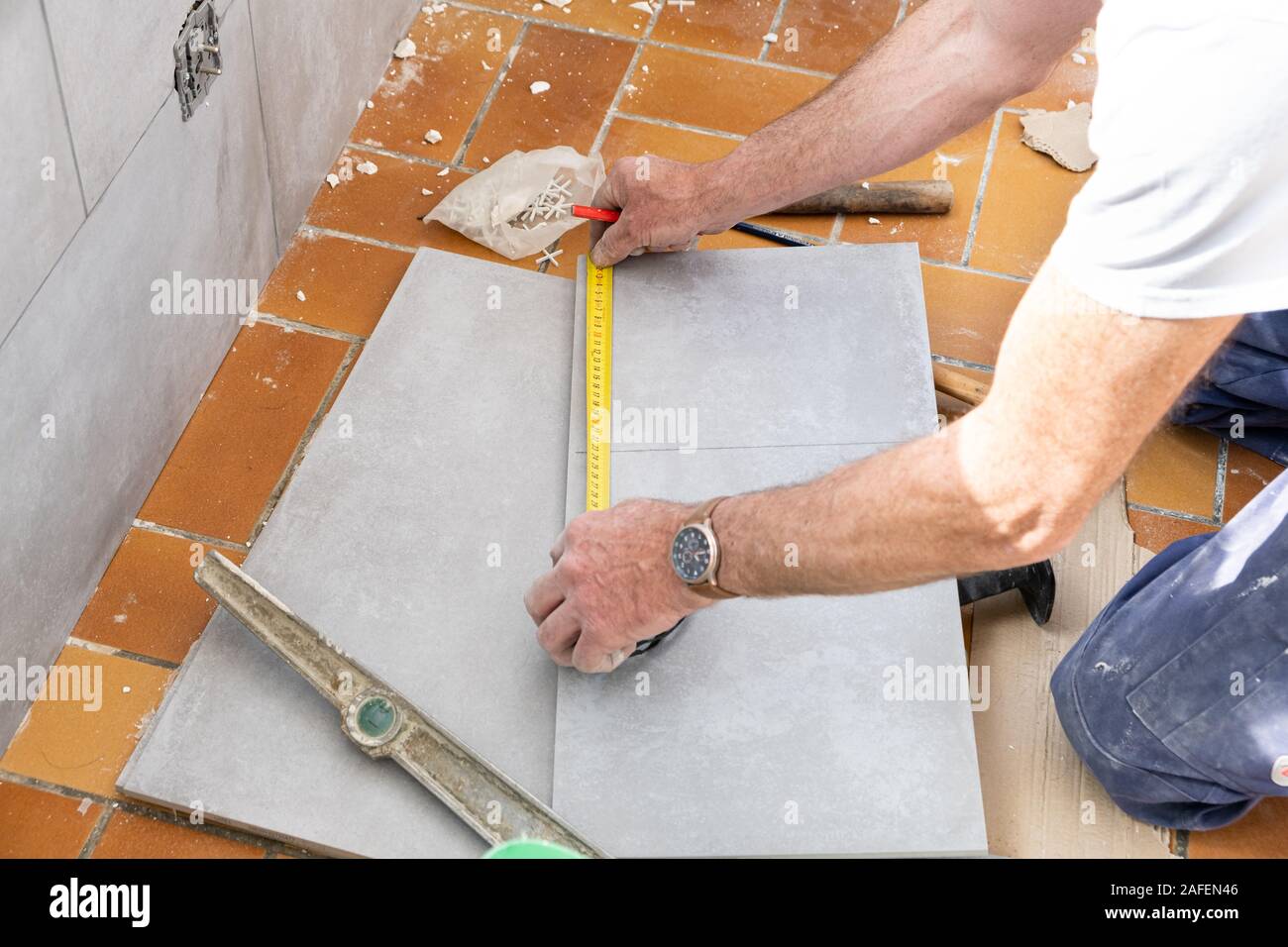 the tiler measures the tile before cutting it Stock Photo - Alamy