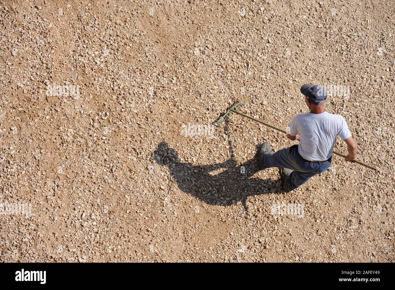 Man doing work raking the ground Stock Photo - Alamy