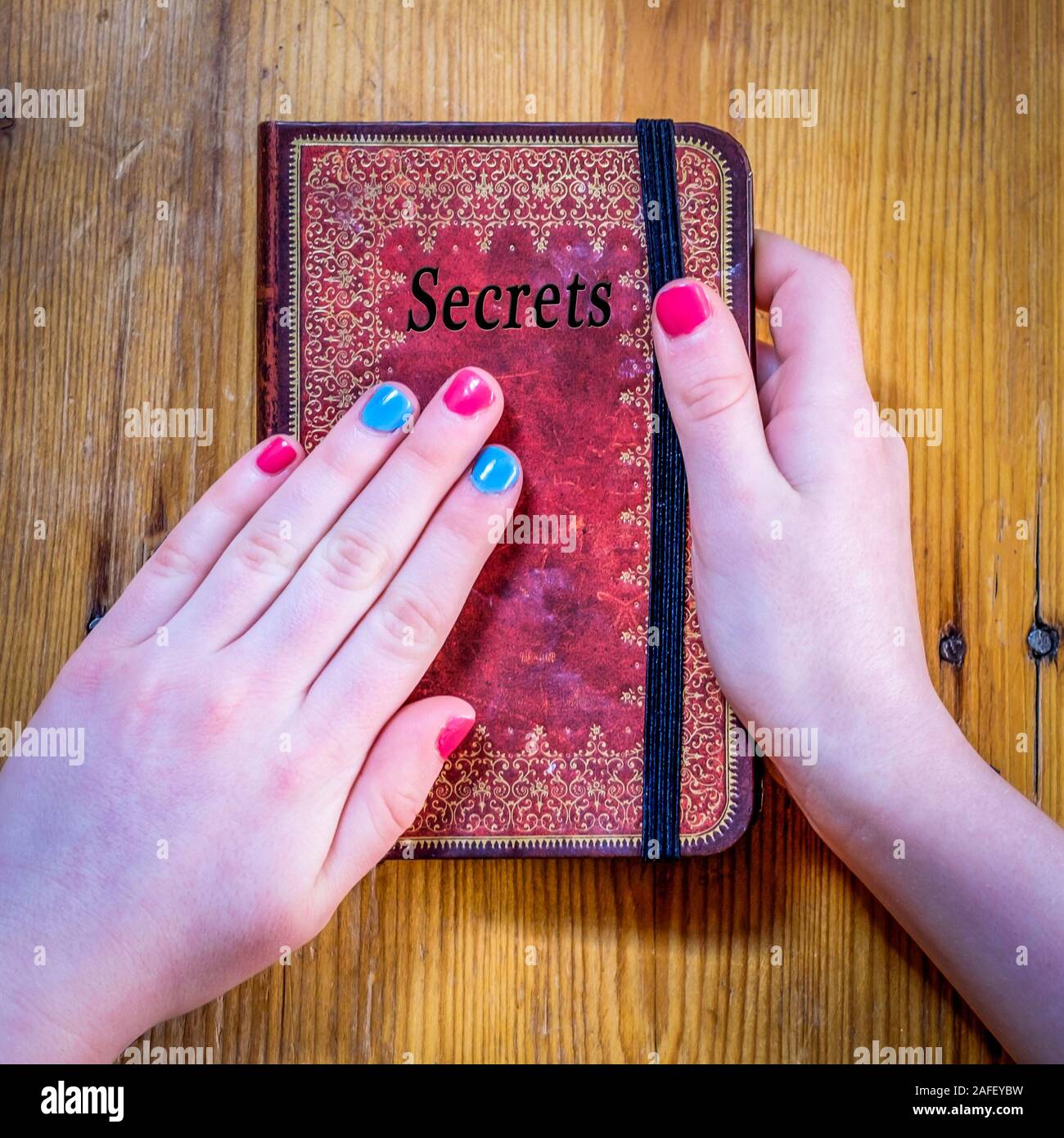 Young girl holding her hands on a diary with the word "secrets Stock ...
