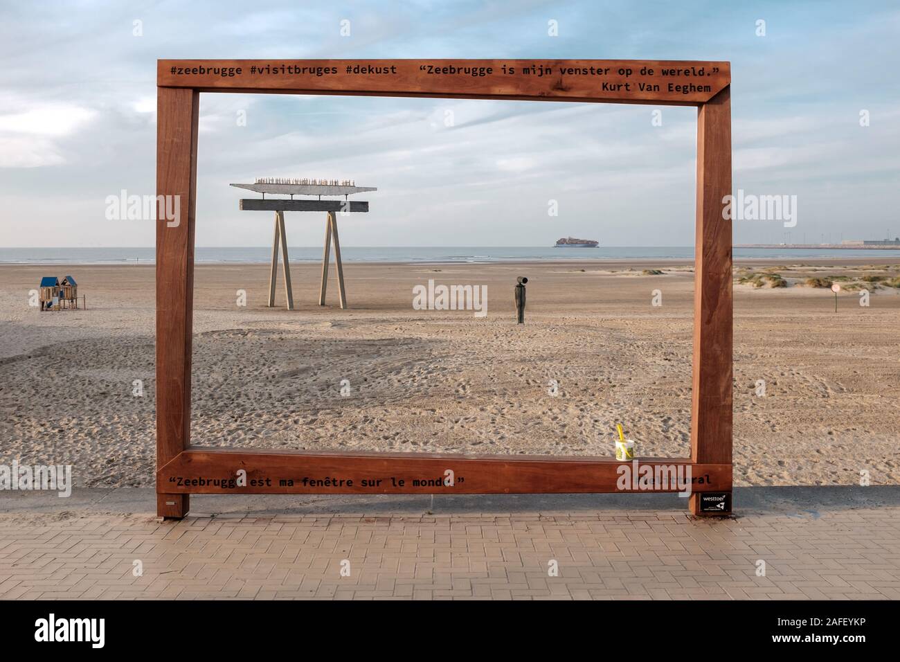 Wooden art framing the beach of Zeebrugge with container vessel in the ...
