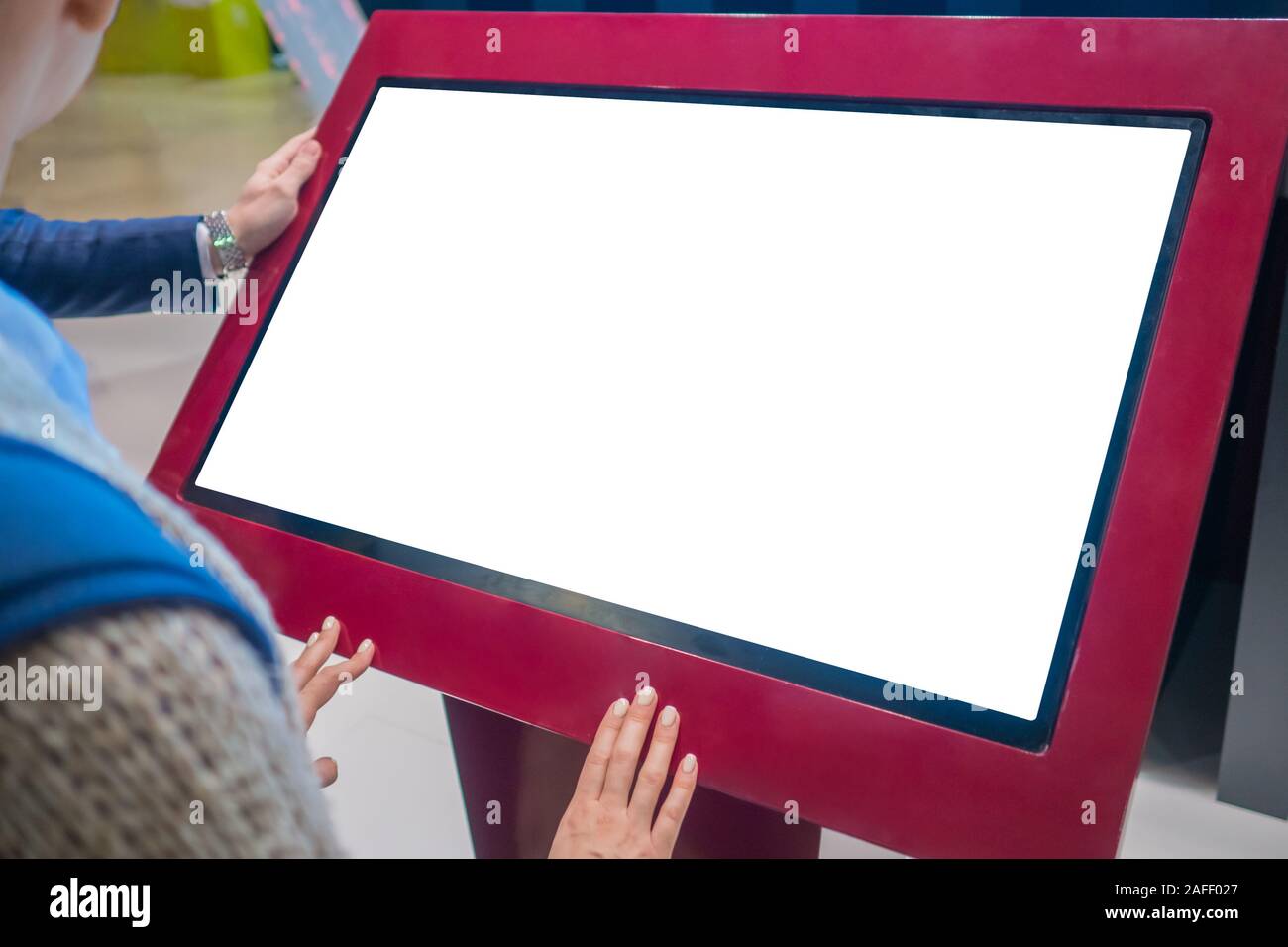 Woman using interactive empty white touchscreen display kiosk at ...