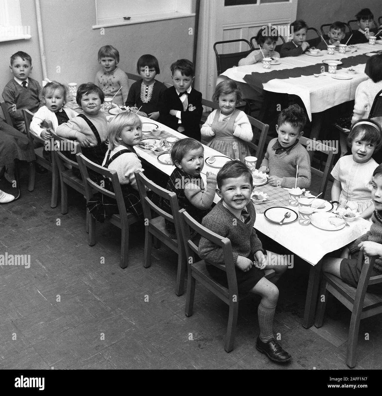 1960s, historical, young children sitting at long tables at a village ...