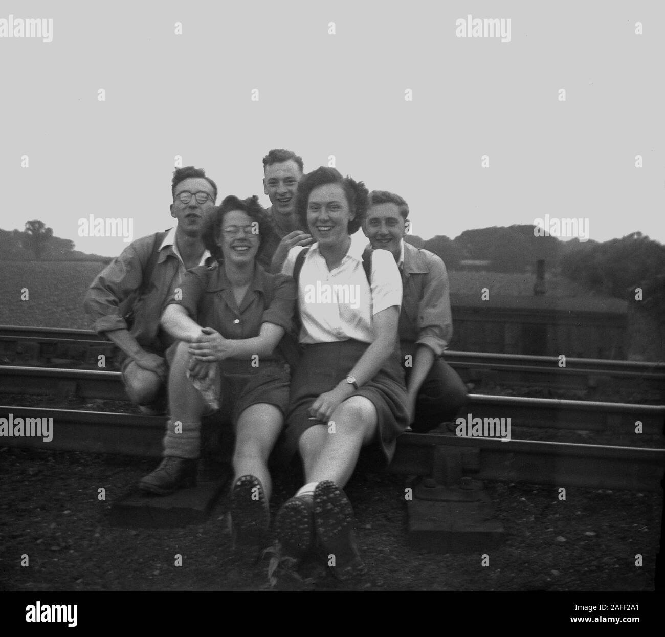1950s, historical, three male and two female walkers sitting outside ...
