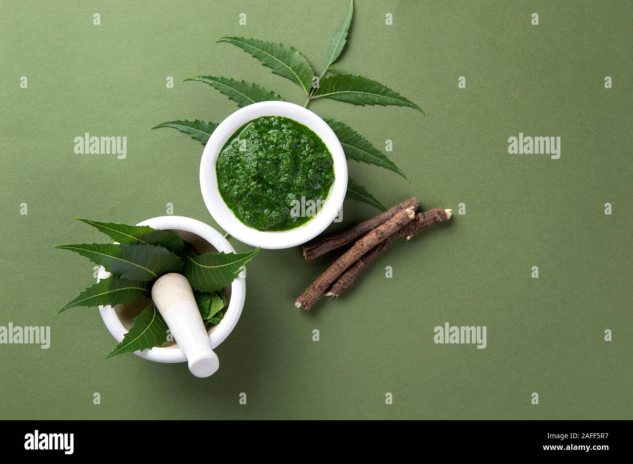 Medicinal Neem leaves in mortar and pestle with paste and twigs on ...