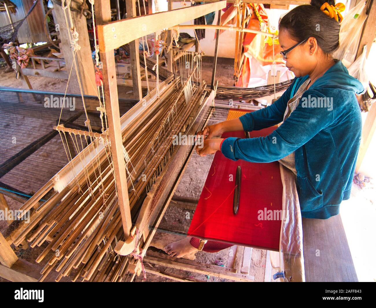 A female weaver producing silk fabric on a traditional hand loom on ...