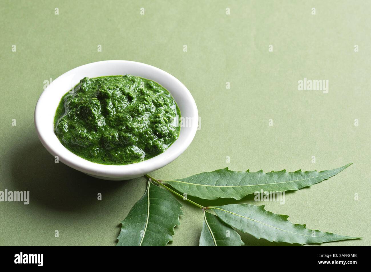 Medicinal Neem leaves with paste in bowl on green background Stock ...