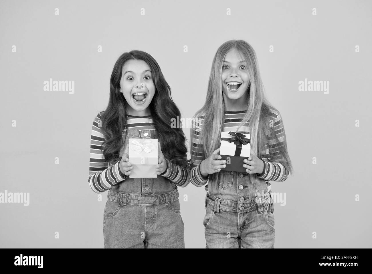 Birthday gift. Happy girls hold gift boxes yellow background. Small ...