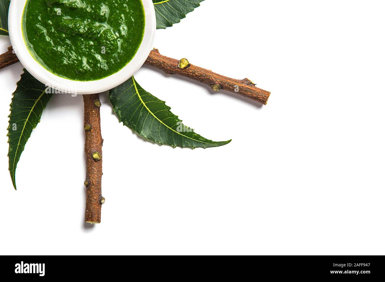 Medicinal Neem leaves with paste in bowl and twigs on white background ...