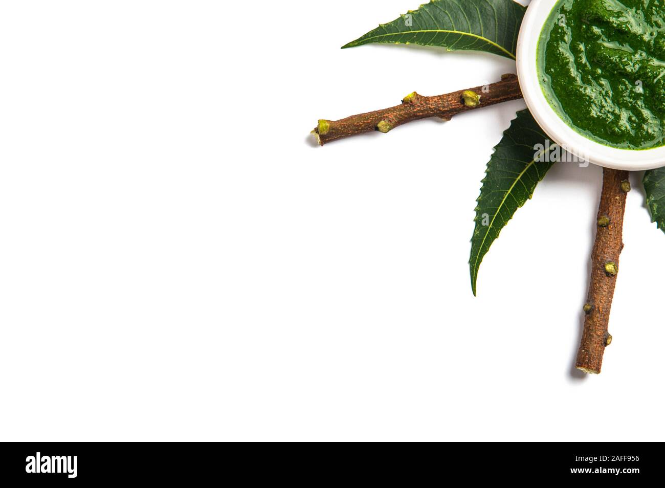Medicinal Neem leaves with paste in bowl and twigs on white background ...