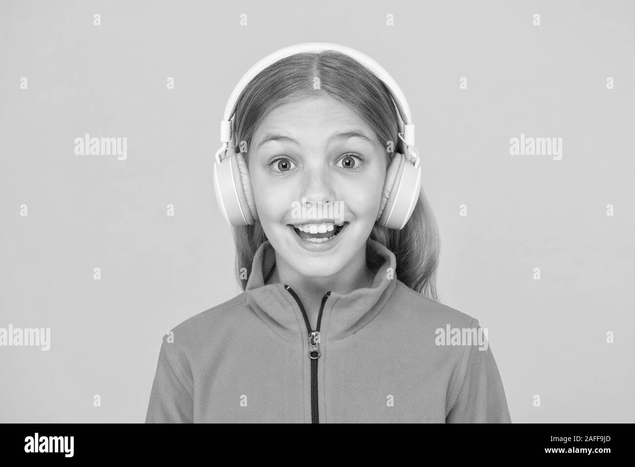 Happy song makes her smile. Happy small girl listen to music on yellow ...