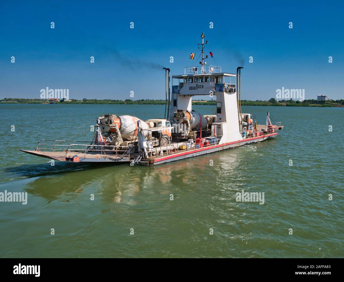 A ferry carrying three cement lorries crosses the Mekong River between ...