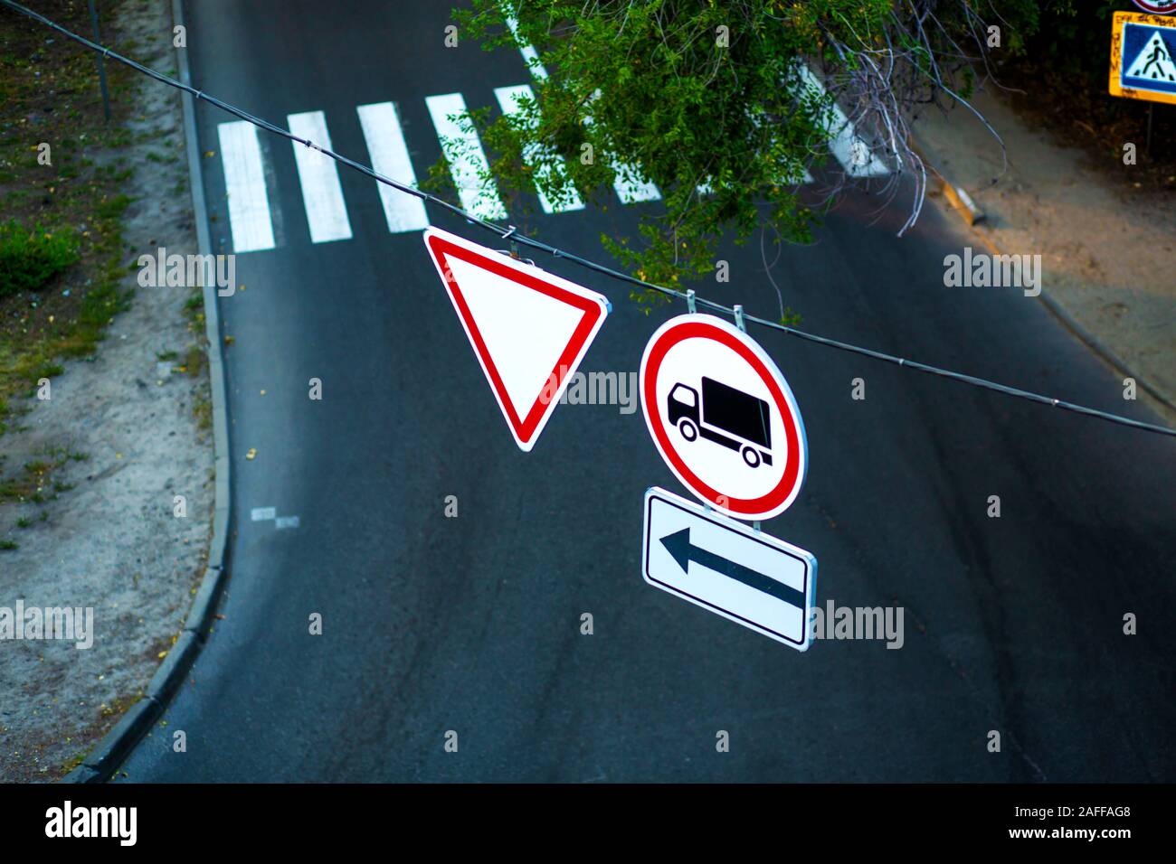 Traffic signs on a wire over the road. A sign obliging to give way. And ...