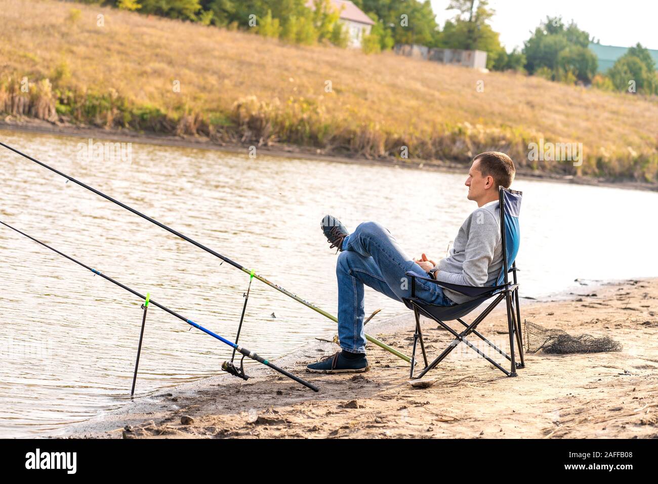 a Man relaxing and fishing by lakeside Stock Photo - Alamy