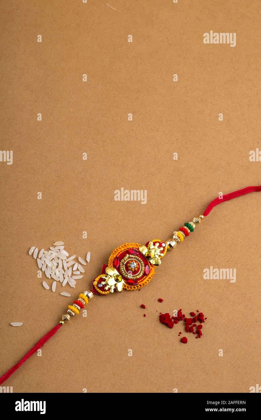 Raksha Bandhan background with an elegant Rakhi, Rice Grains and Kumkum ...