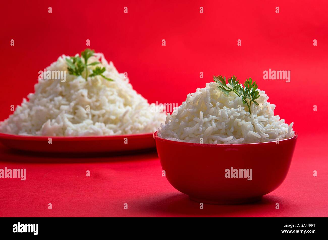 Cooked plain white basmati rice in bowl and plate on red background ...