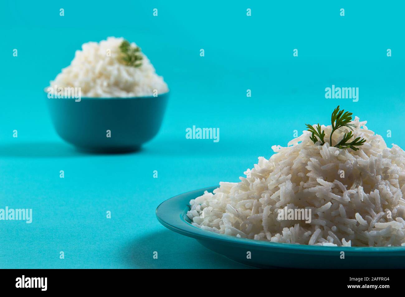 Cooked plain white basmati rice in a blue plate and bowl on blue ...