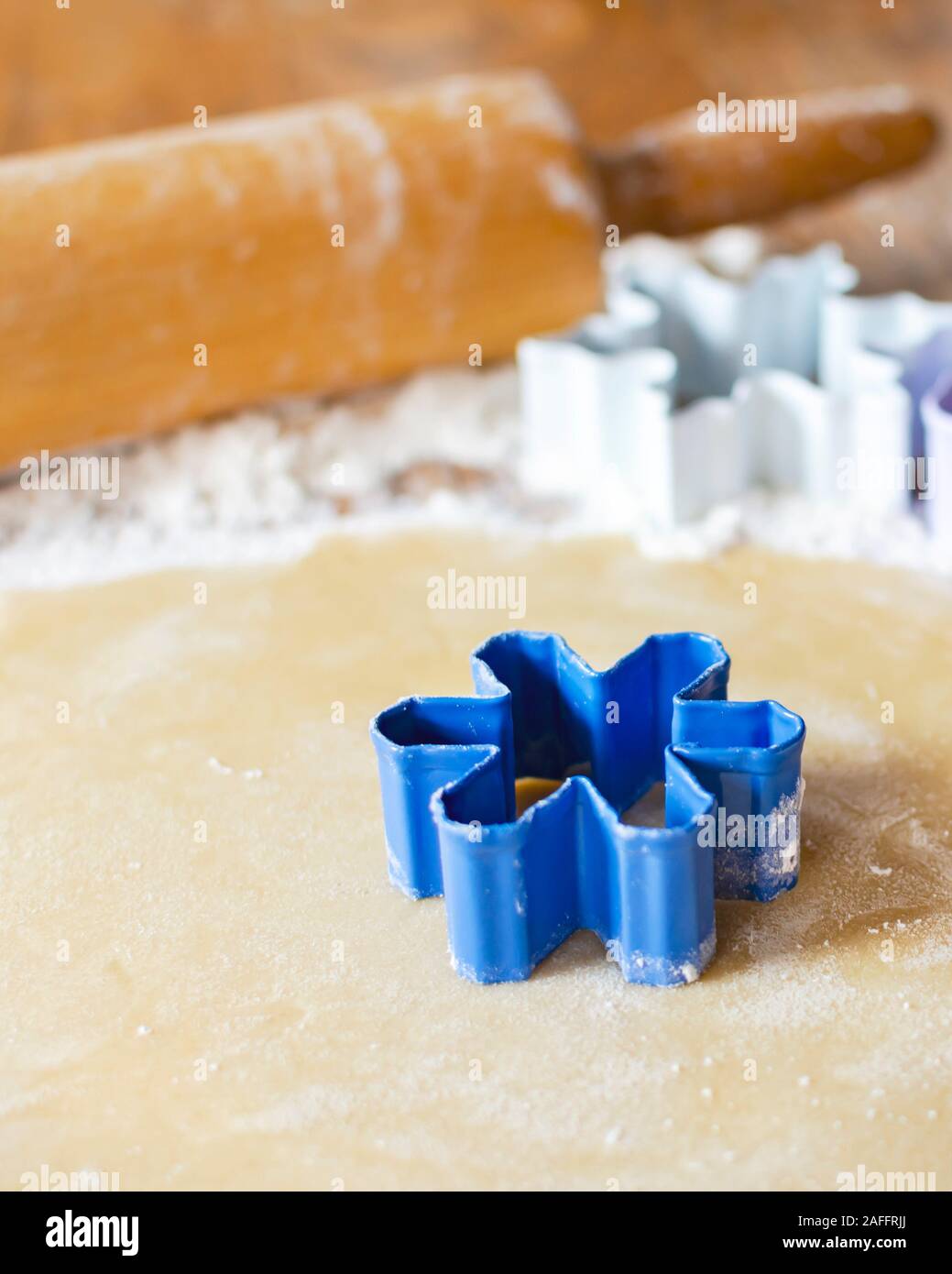 A blue flower cookie cutter on rolled out sugar cookie dough ...