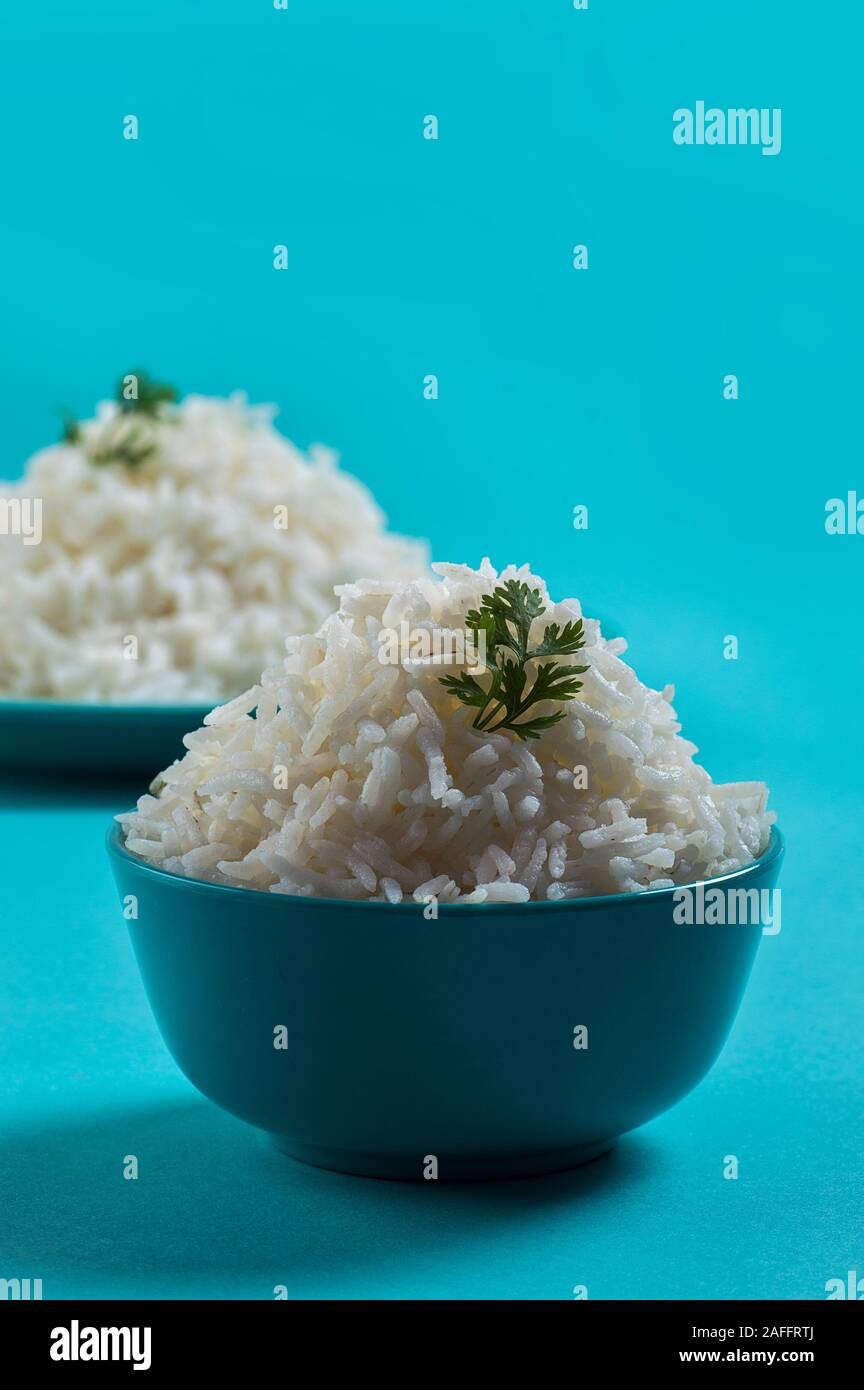 Cooked plain white basmati rice in a blue plate and bowl on blue ...