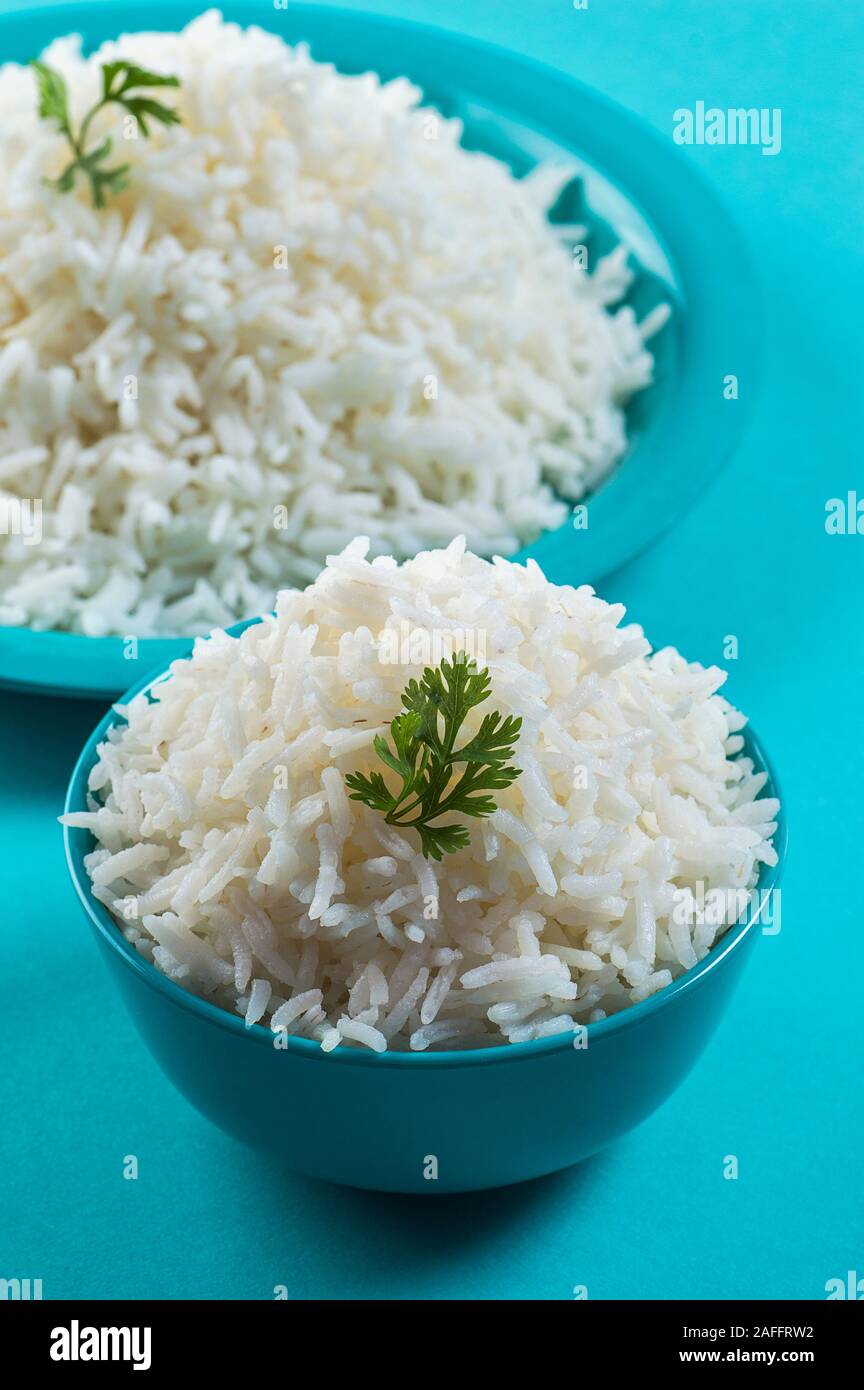 Cooked plain white basmati rice in a blue plate and bowl on blue ...