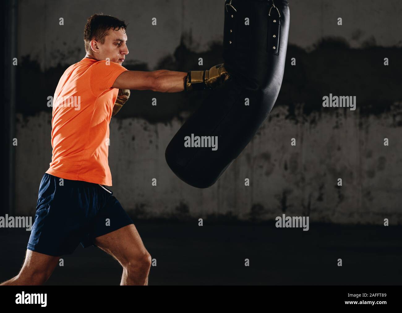 Silhouette male boxer hitting a huge punching bag at a boxing studio ...
