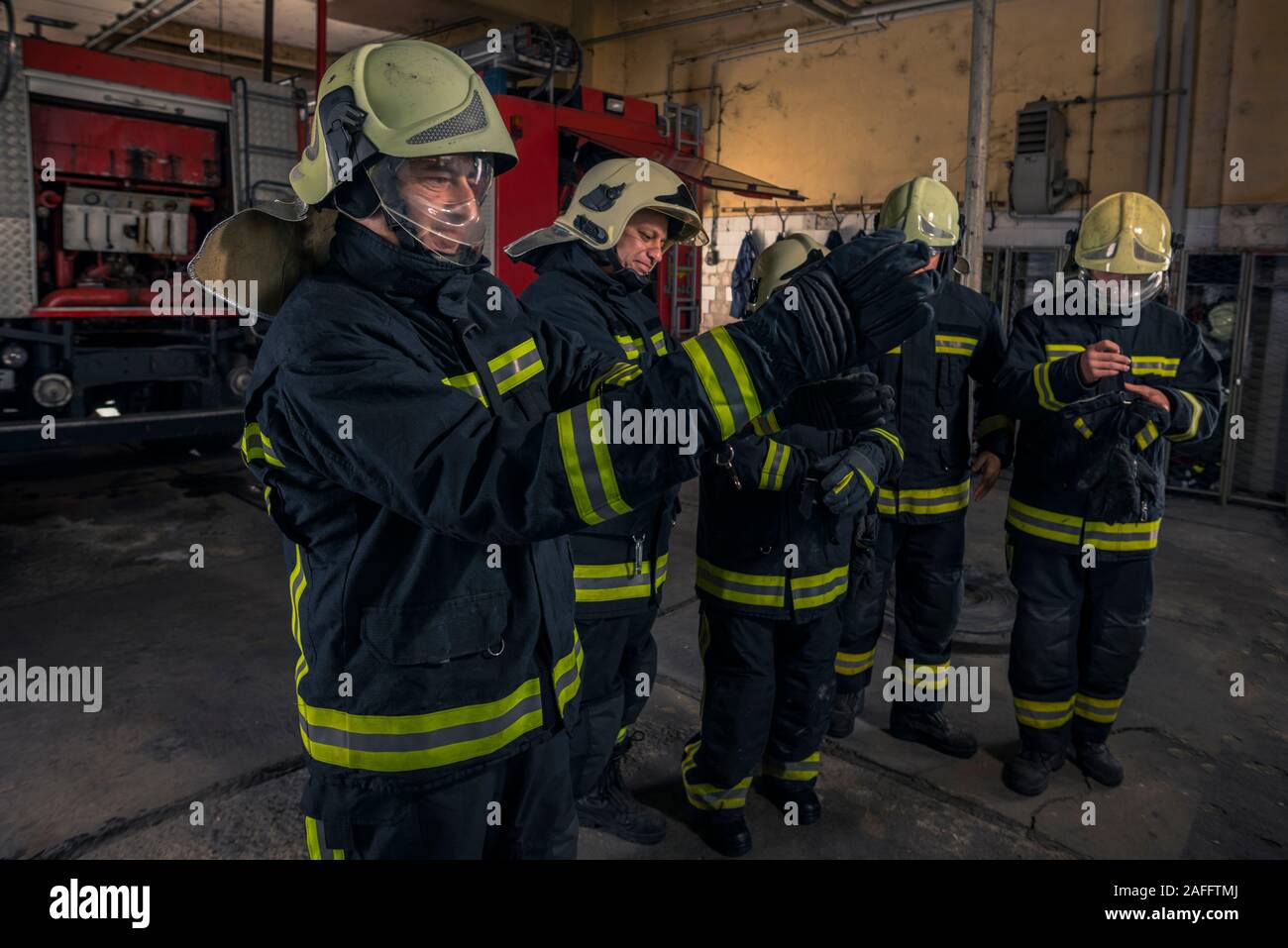 Firemen preparing for emergency service. Firefighters putting on gloves ...
