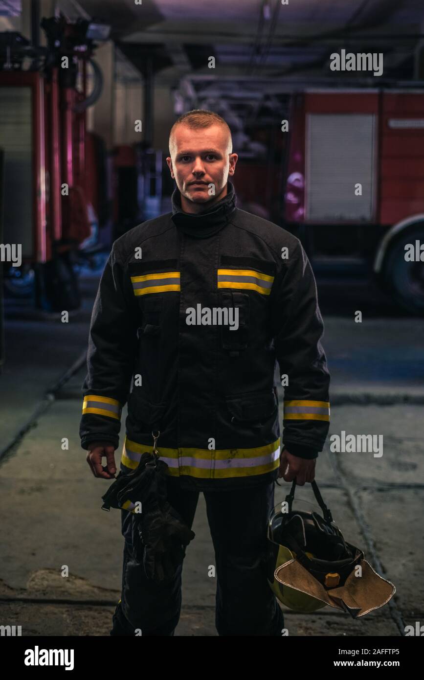 Portrait of young fireman standing inside the fire station Stock Photo ...
