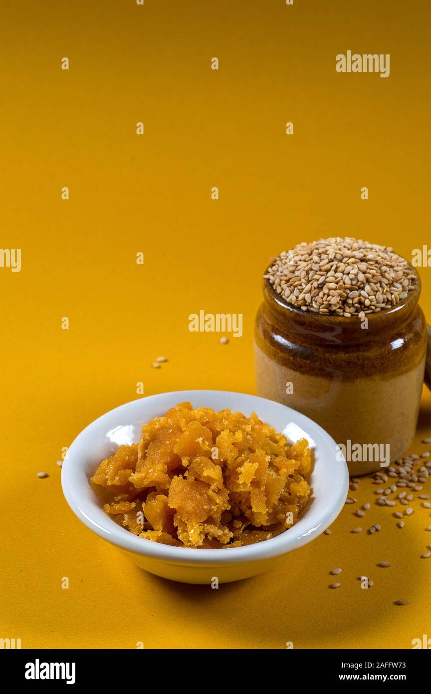 Sesame Seeds in clay pot with Jaggery in bowl on yellow background ...