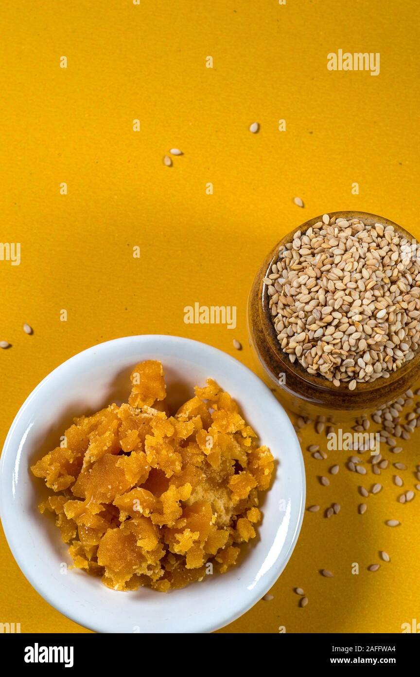 Sesame Seeds in clay pot with Jaggery in bowl on yellow background ...