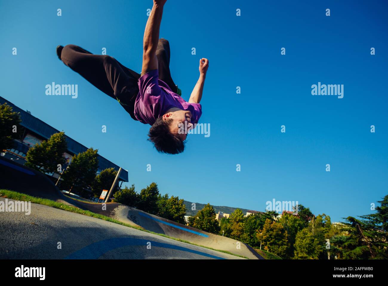 Muscular man in midair while performing a side flip at the skate park ...