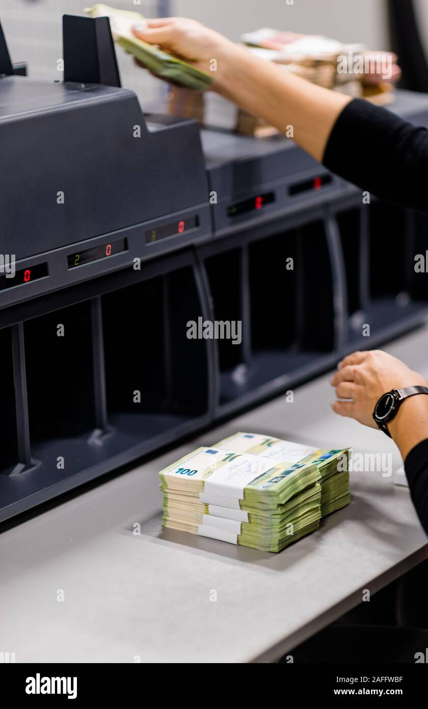 Office woman loading multiple bundles of euro € banknotes in automatic ...