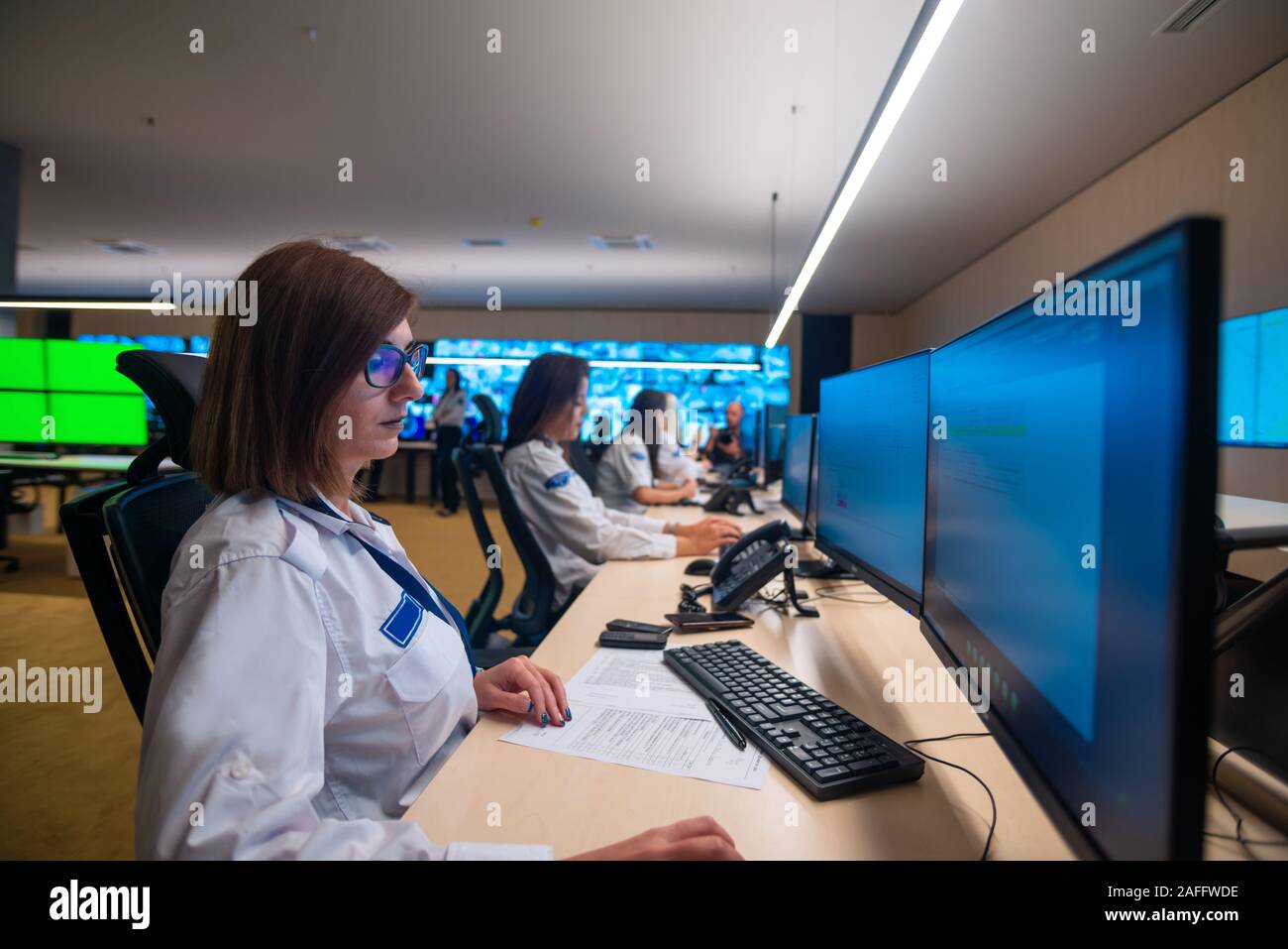 Female security guards working on computers while sitting in the main ...