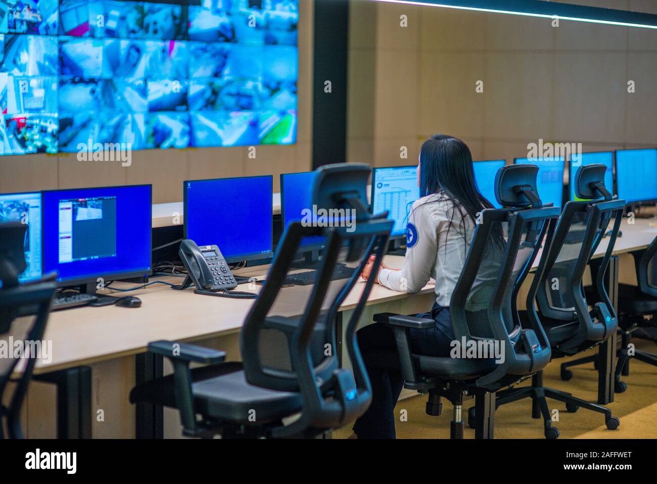 Female security guard sitting back and monitoring modern CCTV cameras ...